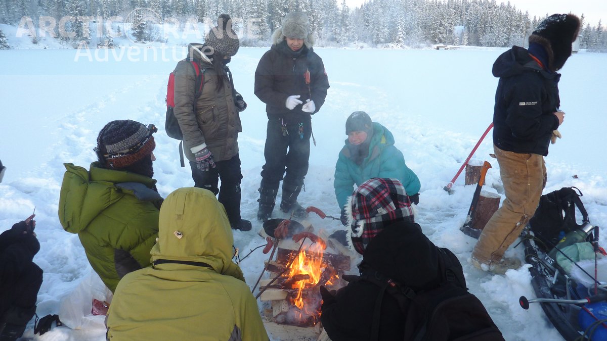 Group enjoying the camp fire while ice fishing | Arctic Range Adventure